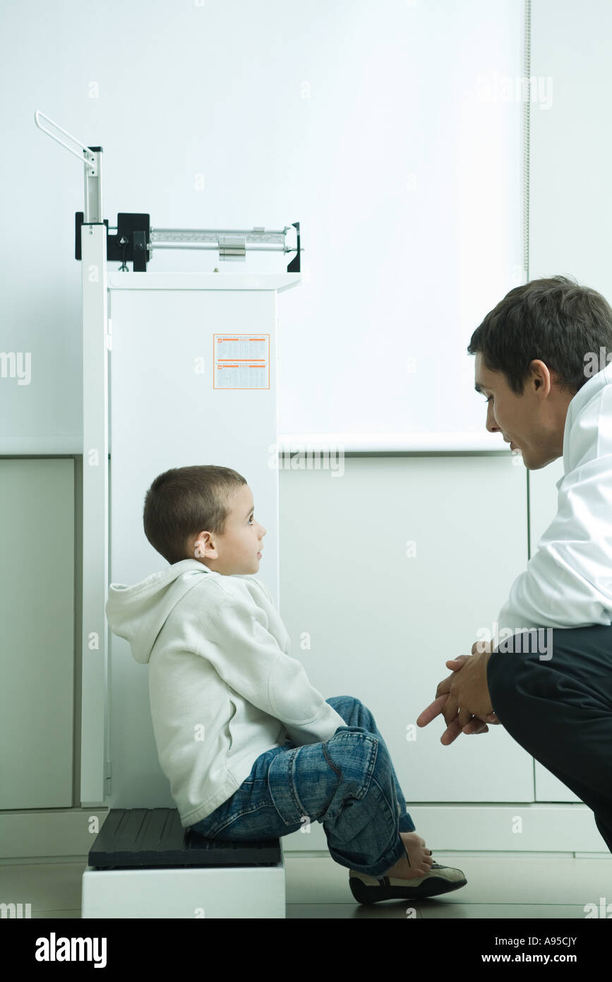 Boy sitting on scale talking to doctor in doctor's office Stock Photo ...