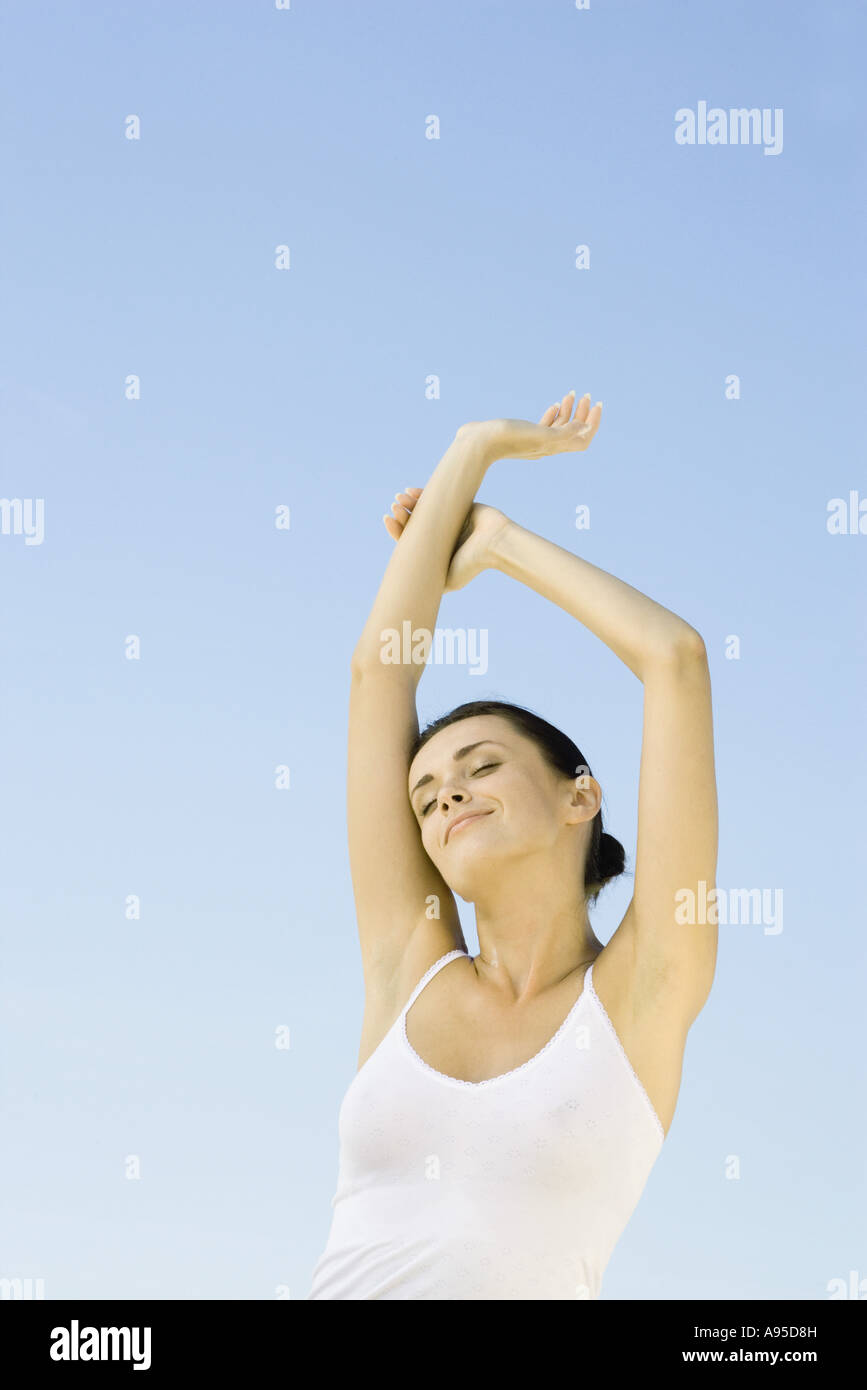 Woman stretching arms overhead, sky in background, low angle view Stock ...