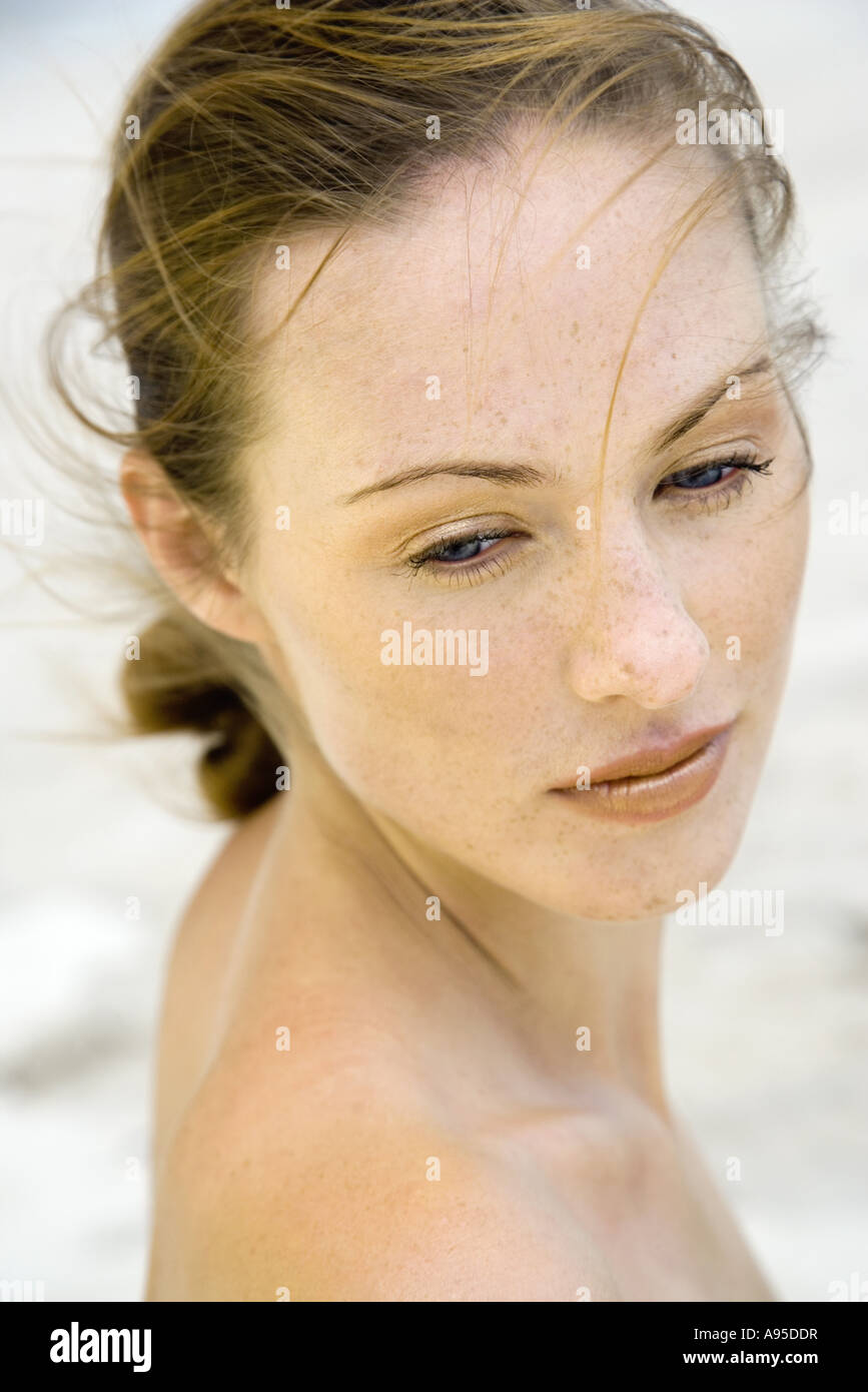 Woman looking over shoulder, hair being tousled by the wind, head and ...
