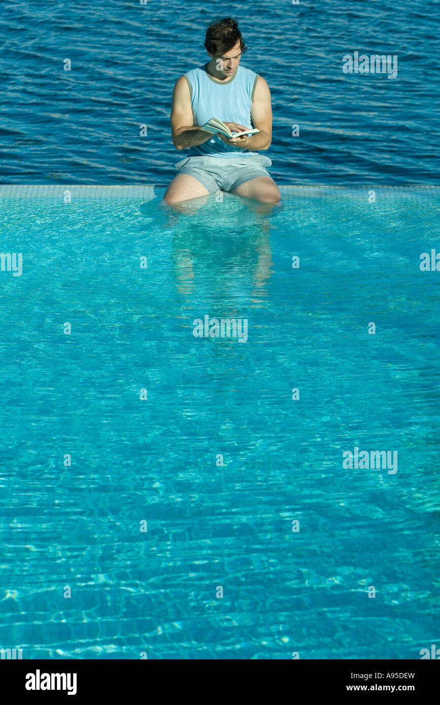 Man sitting in infinity pool, reading Stock Photo - Alamy