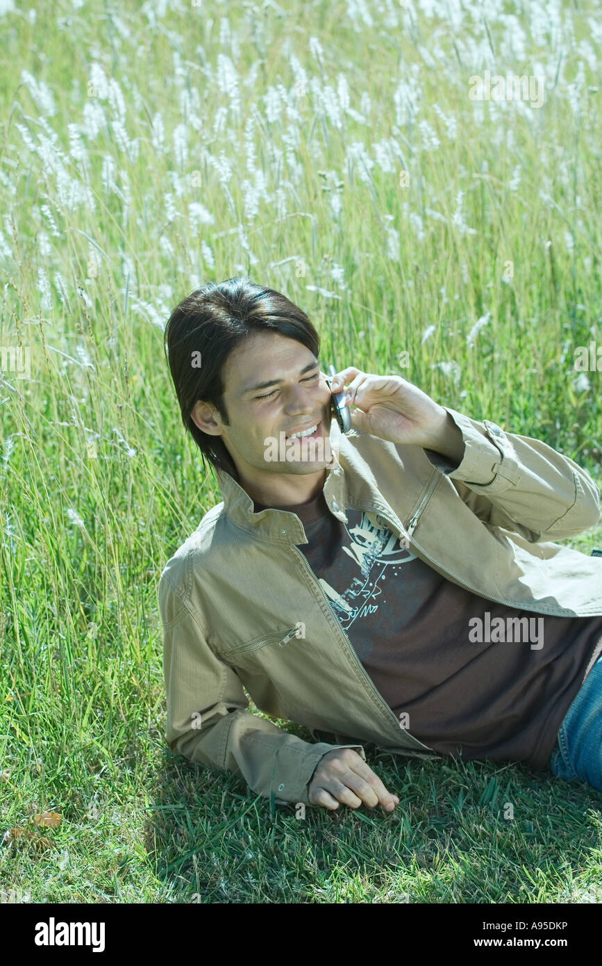 Man lounging in field, using cell phone, eyes closed Stock Photo - Alamy