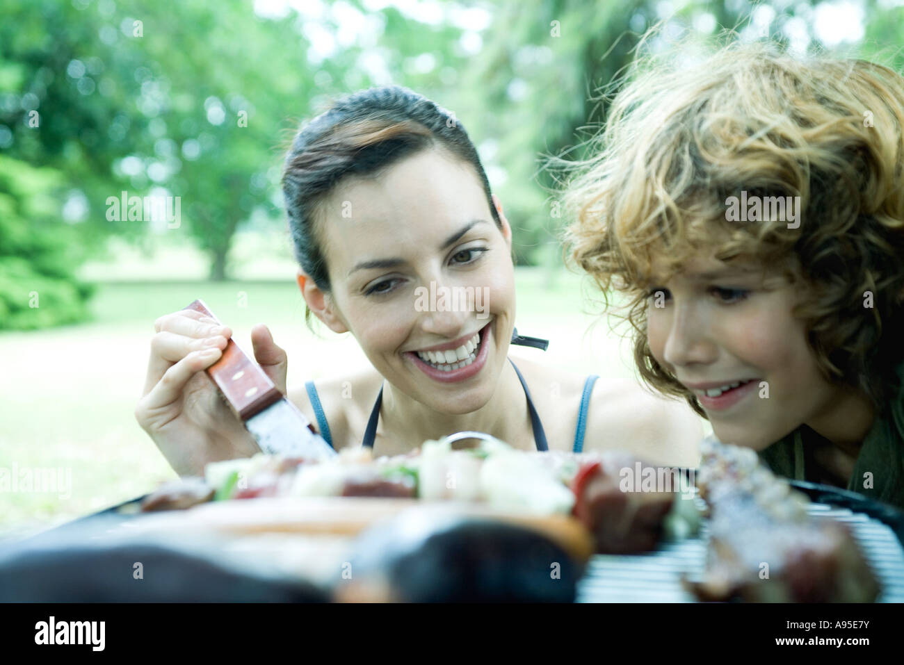 Family having cookout, woman and boy looking at food grilling Stock ...