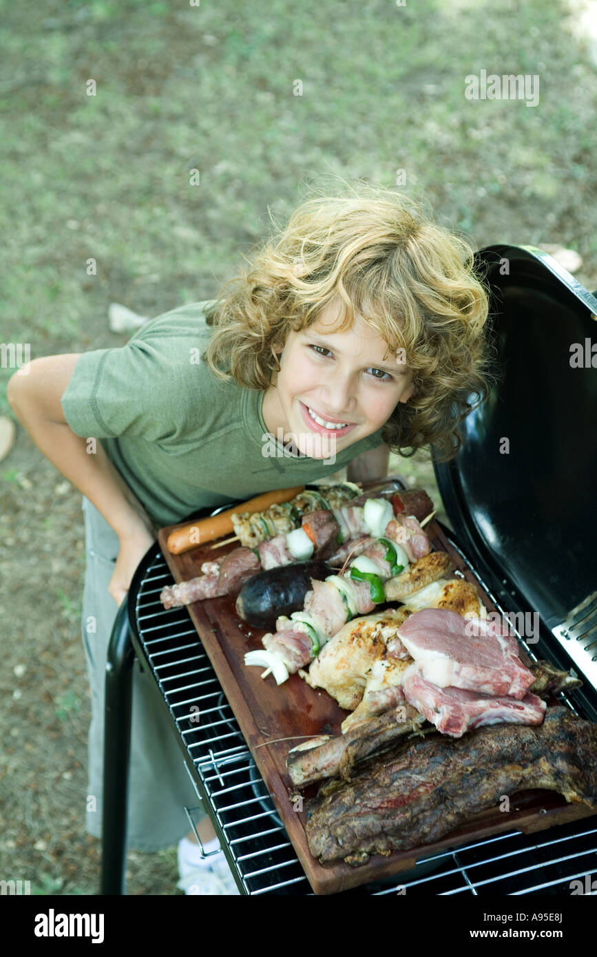 Boy leaning over grilling food, smiling at camera Stock Photo - Alamy
