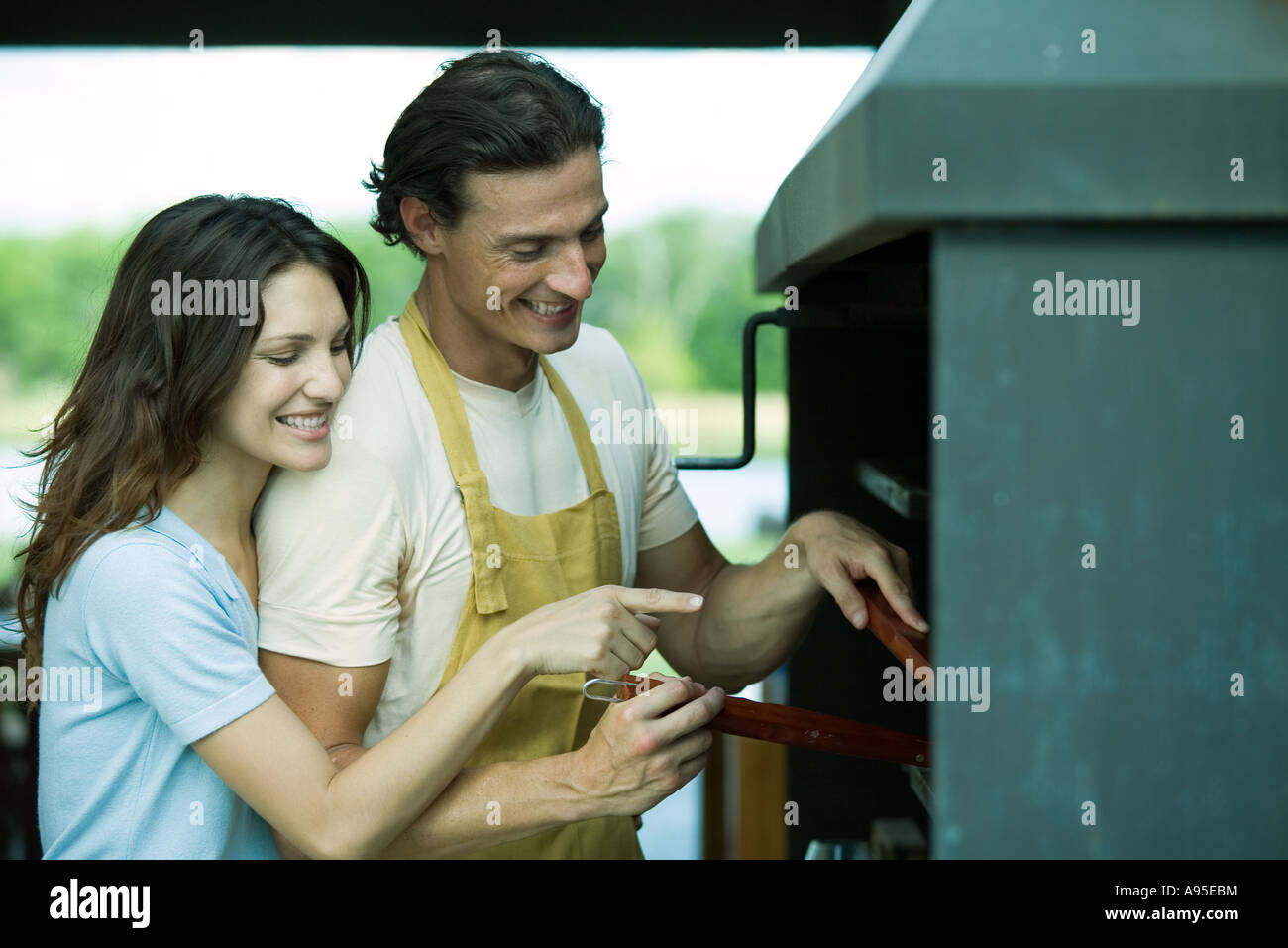 Couple having cookout together, woman pointing to barbecue Stock Photo ...