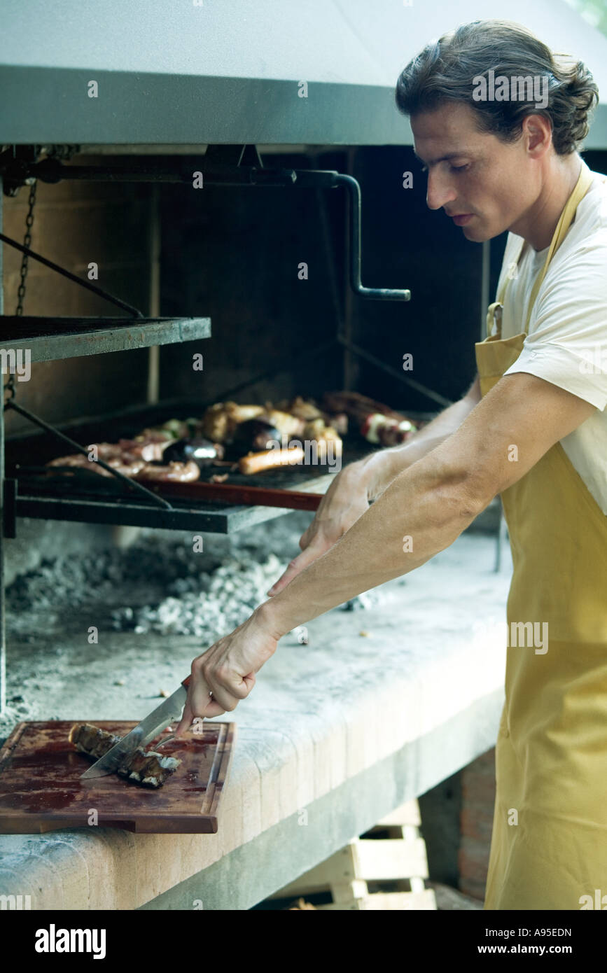 Man barbecuing, cutting piece of meat Stock Photo - Alamy