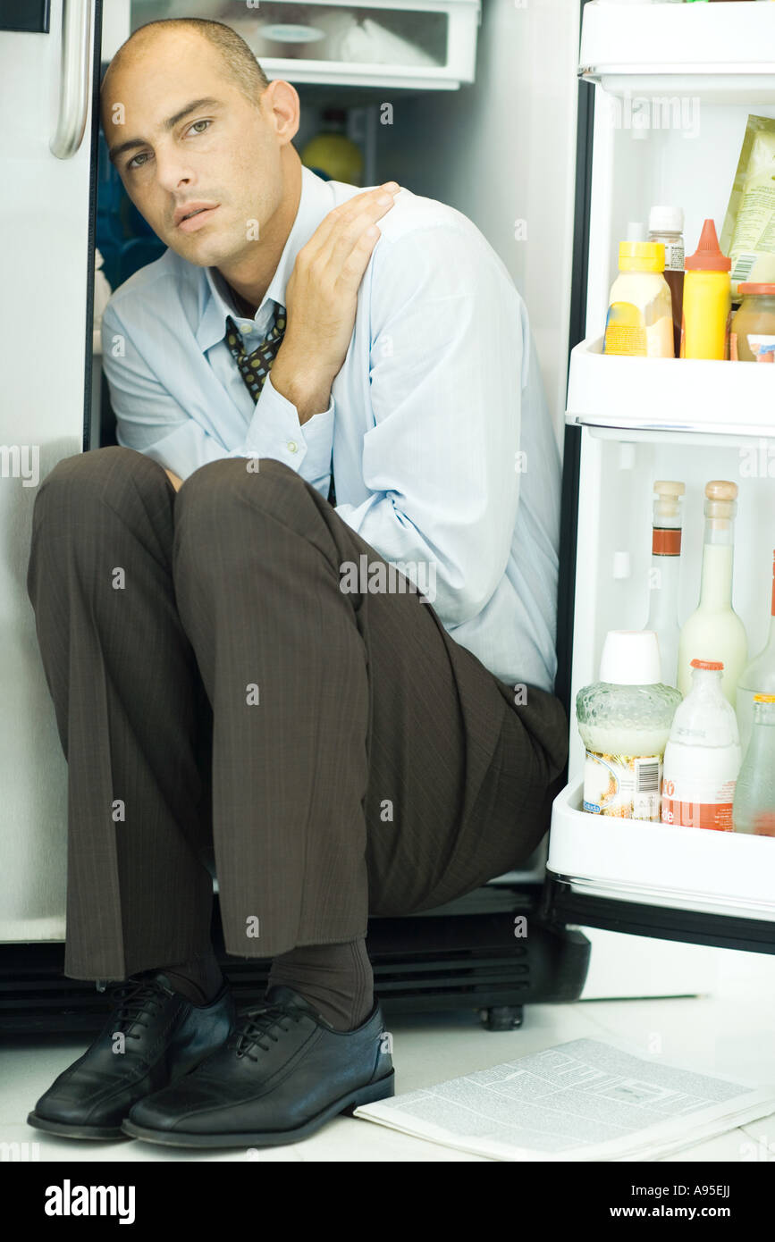 Man sitting in open refrigerator, crossing arms Stock Photo - Alamy