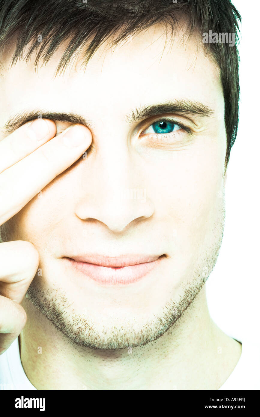 Young man holding fingers over eye, close-up, front view of face Stock ...