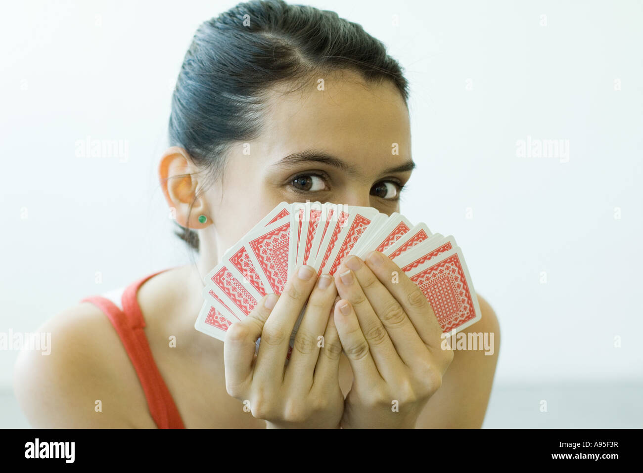 Teenage girl looking at camera over hand of cards Stock Photo - Alamy