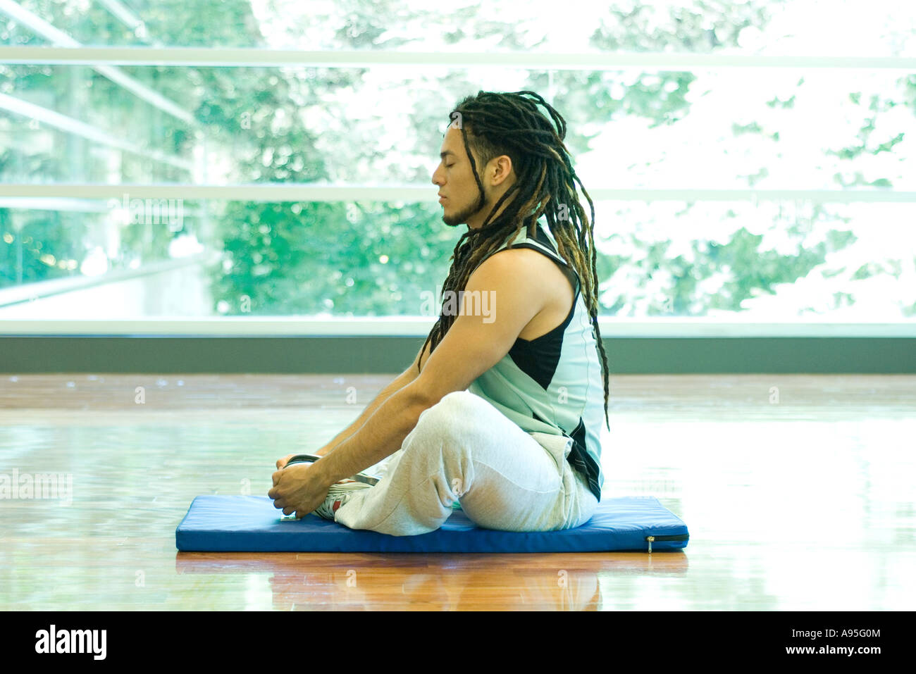 Man sitting in lotus position, side view Stock Photo - Alamy