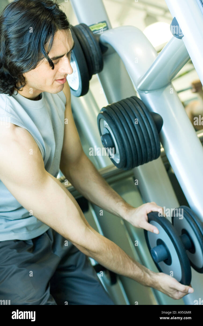 Man taking weight from rack Stock Photo - Alamy