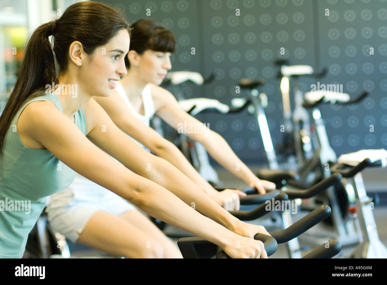 Two women riding exercise bikes Stock Photo - Alamy