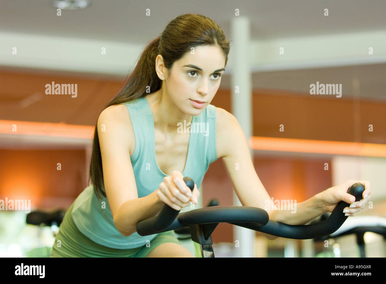 Woman riding exercise bike Stock Photo - Alamy