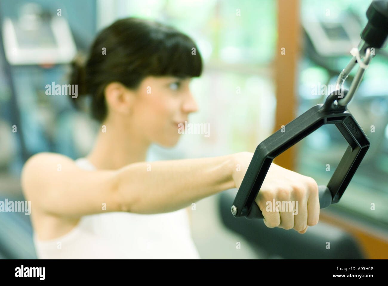Woman pulling handle of exercise machine Stock Photo - Alamy