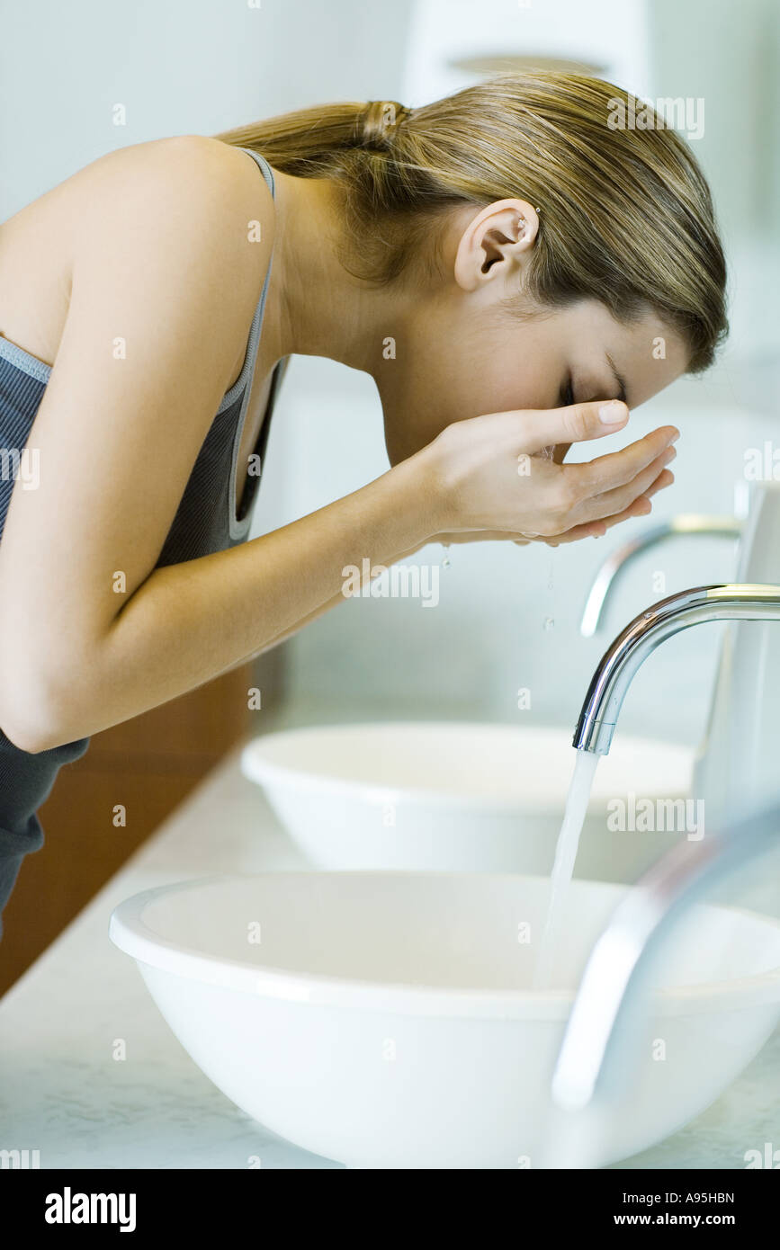 Woman washing face over sink, side view Stock Photo - Alamy