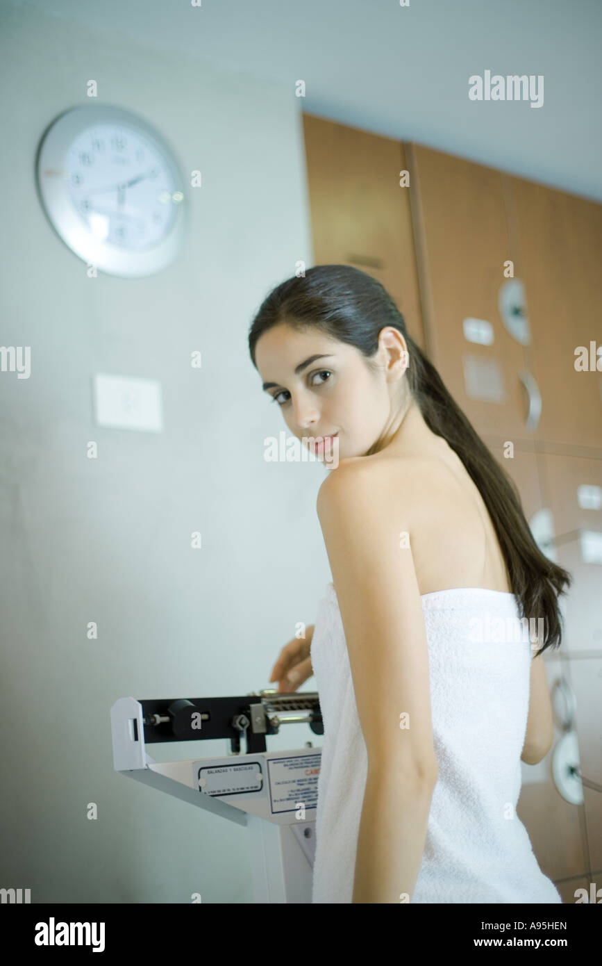 Woman wrapped in towel, standing on scale, looking at camera Stock ...