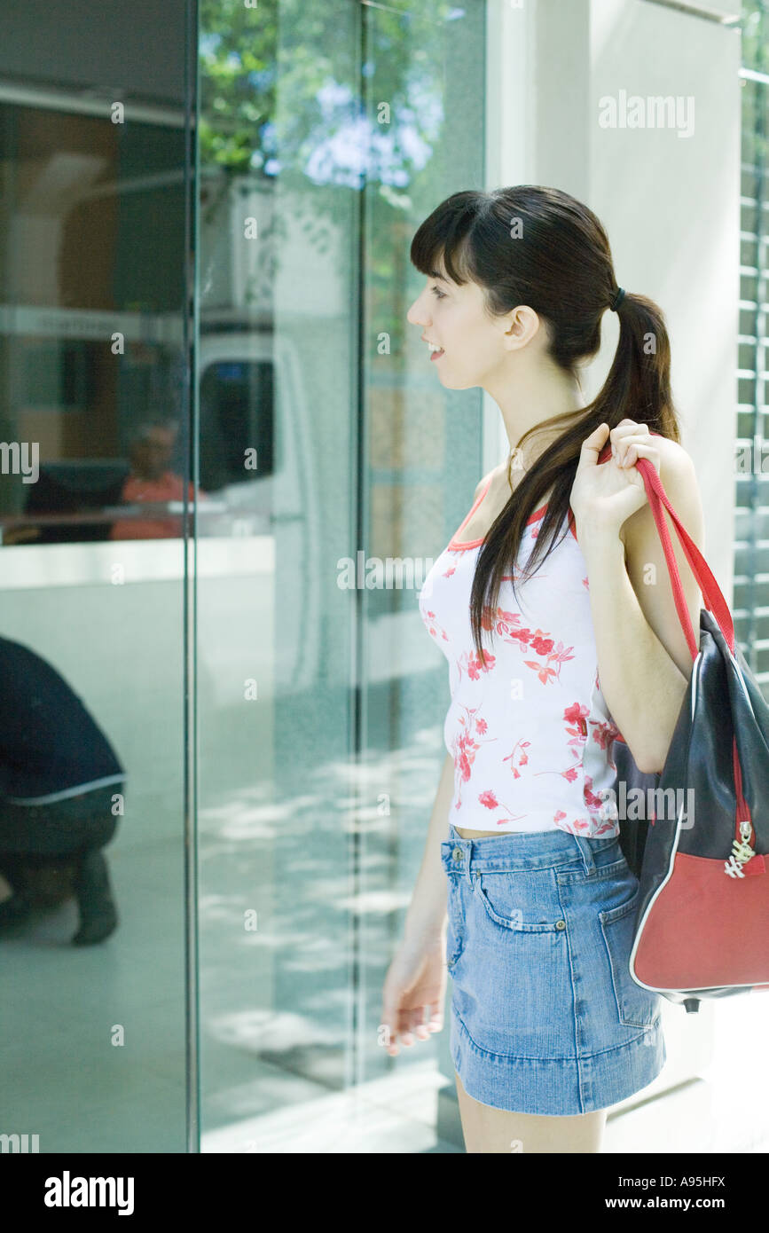 Woman looking into building entrance, side view Stock Photo - Alamy