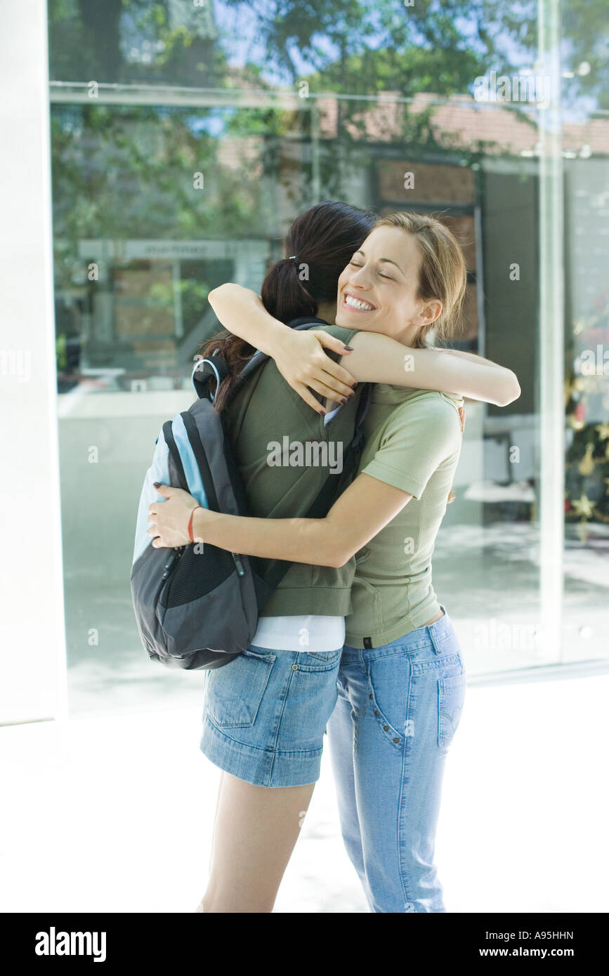 Two young women hugging each other, side view Stock Photo - Alamy
