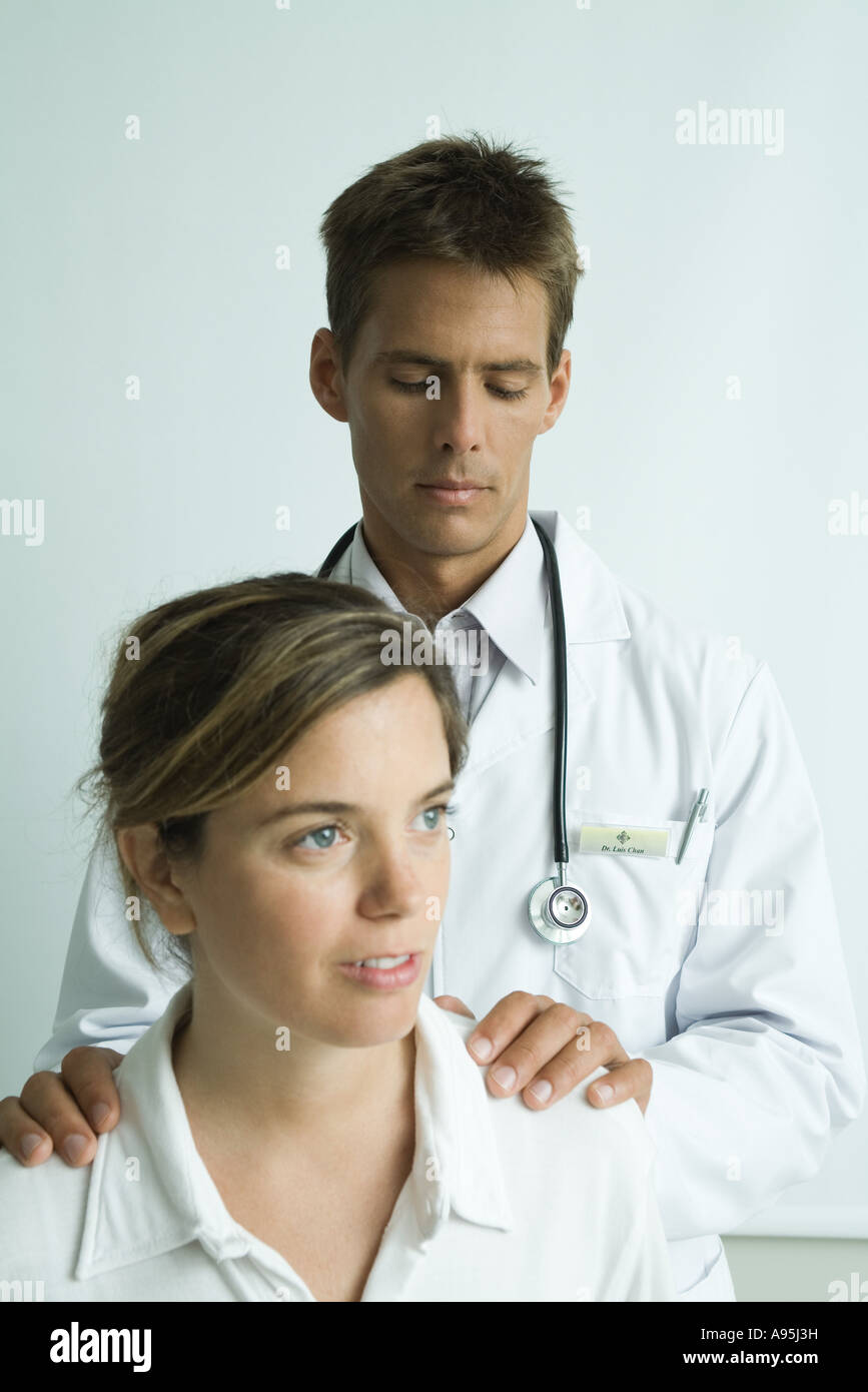 Doctor standing behind woman, hands on her shoulders Stock Photo - Alamy