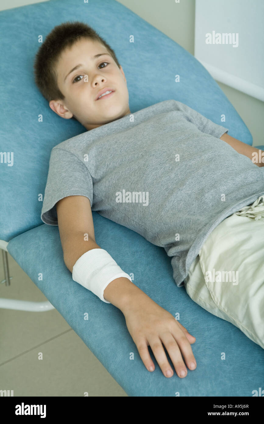 Boy lying on examination table with bandage around arm Stock Photo - Alamy