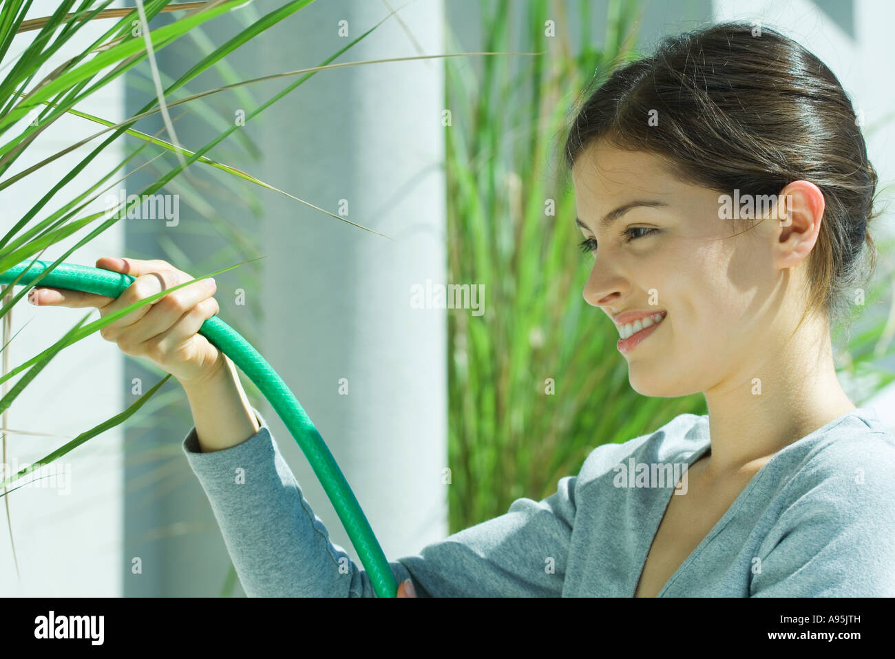 Young woman watering plants with garden hose Stock Photo - Alamy