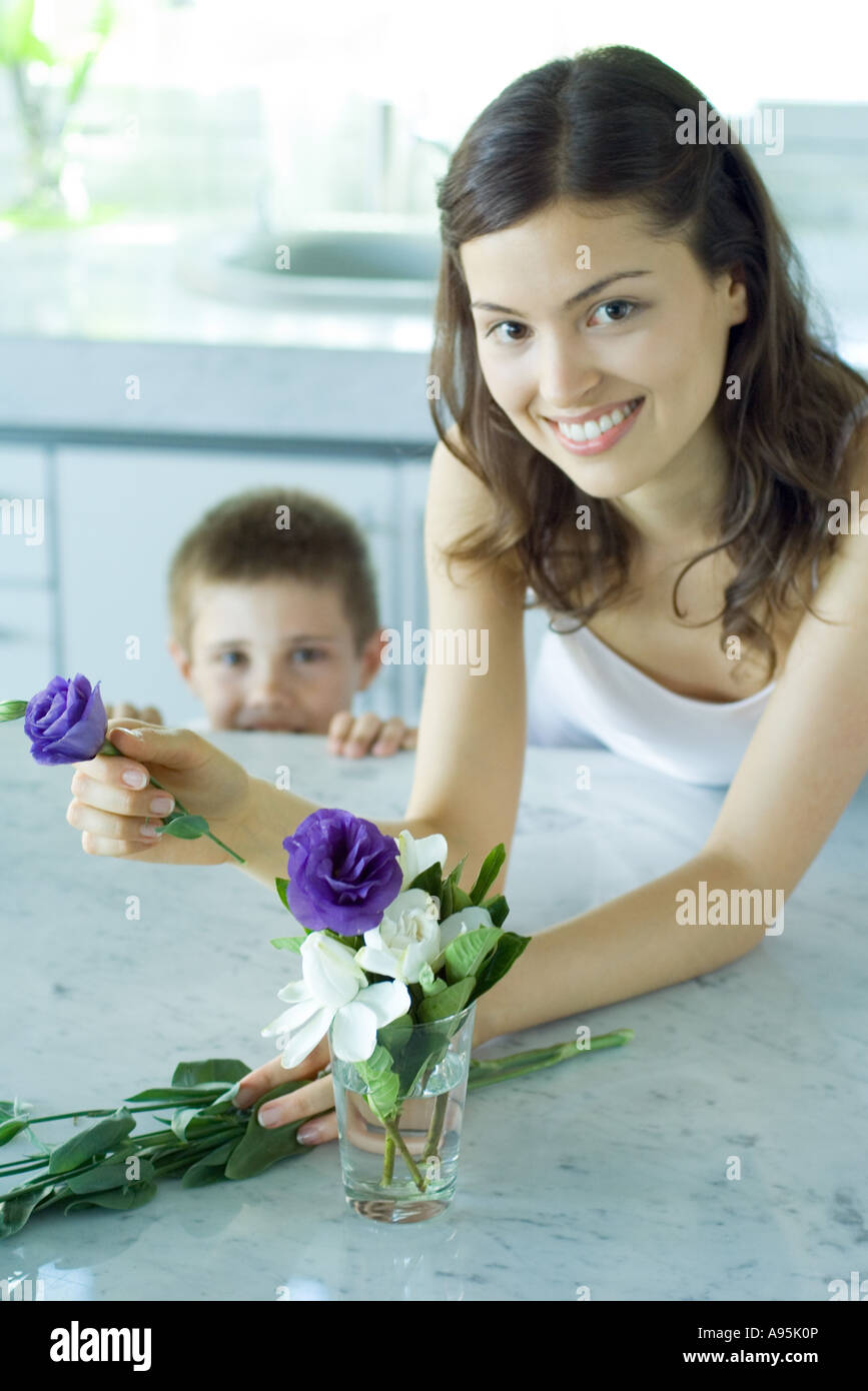 Young woman making fresh flower arrangement, next to boy, smiling Stock ...