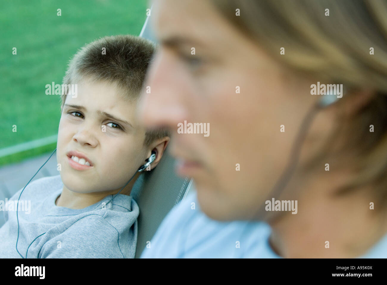 Man and boy listening to earphones together, focus on boy Stock Photo ...