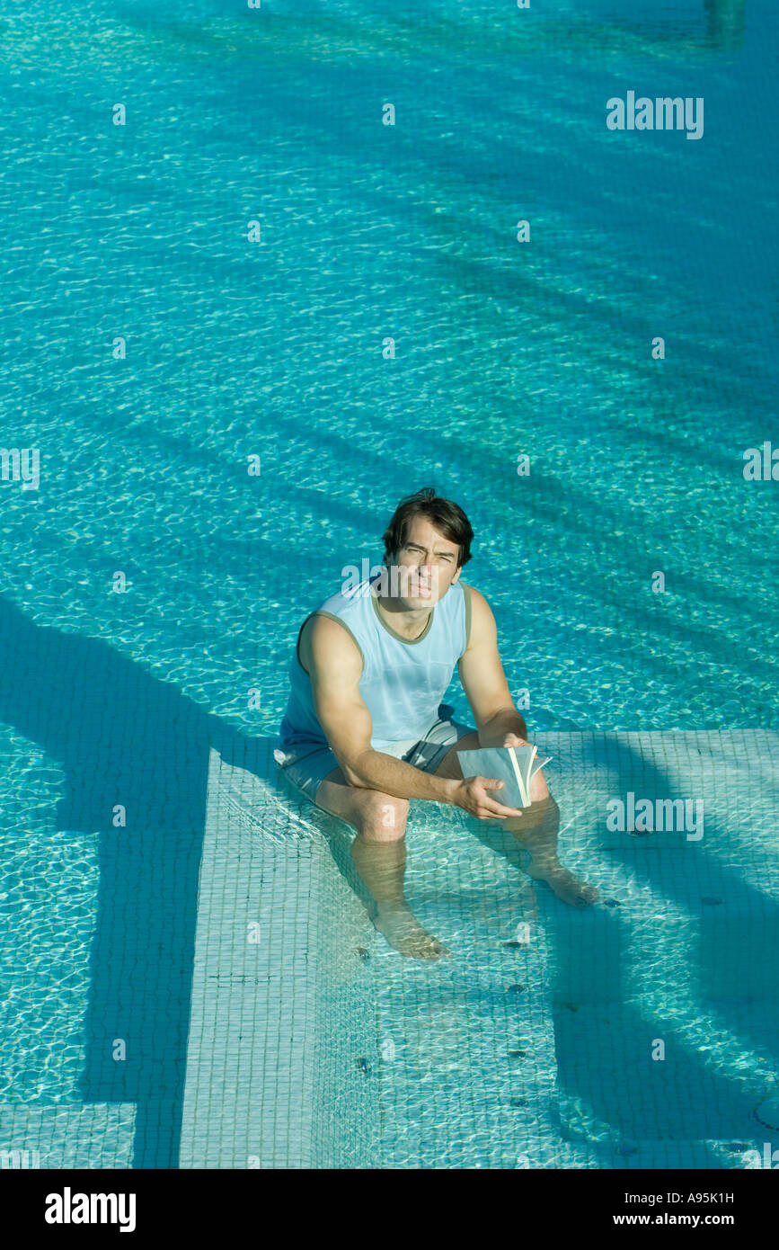 Man sitting in pool, reading, looking up at camera Stock Photo - Alamy