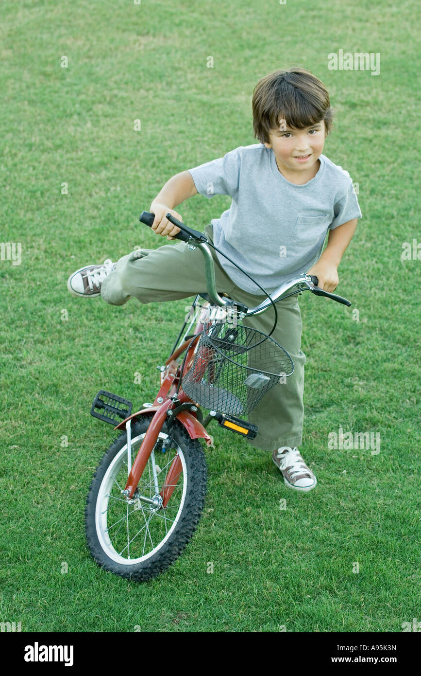 Boy getting on bike, on grass, high angle view, full length Stock Photo ...