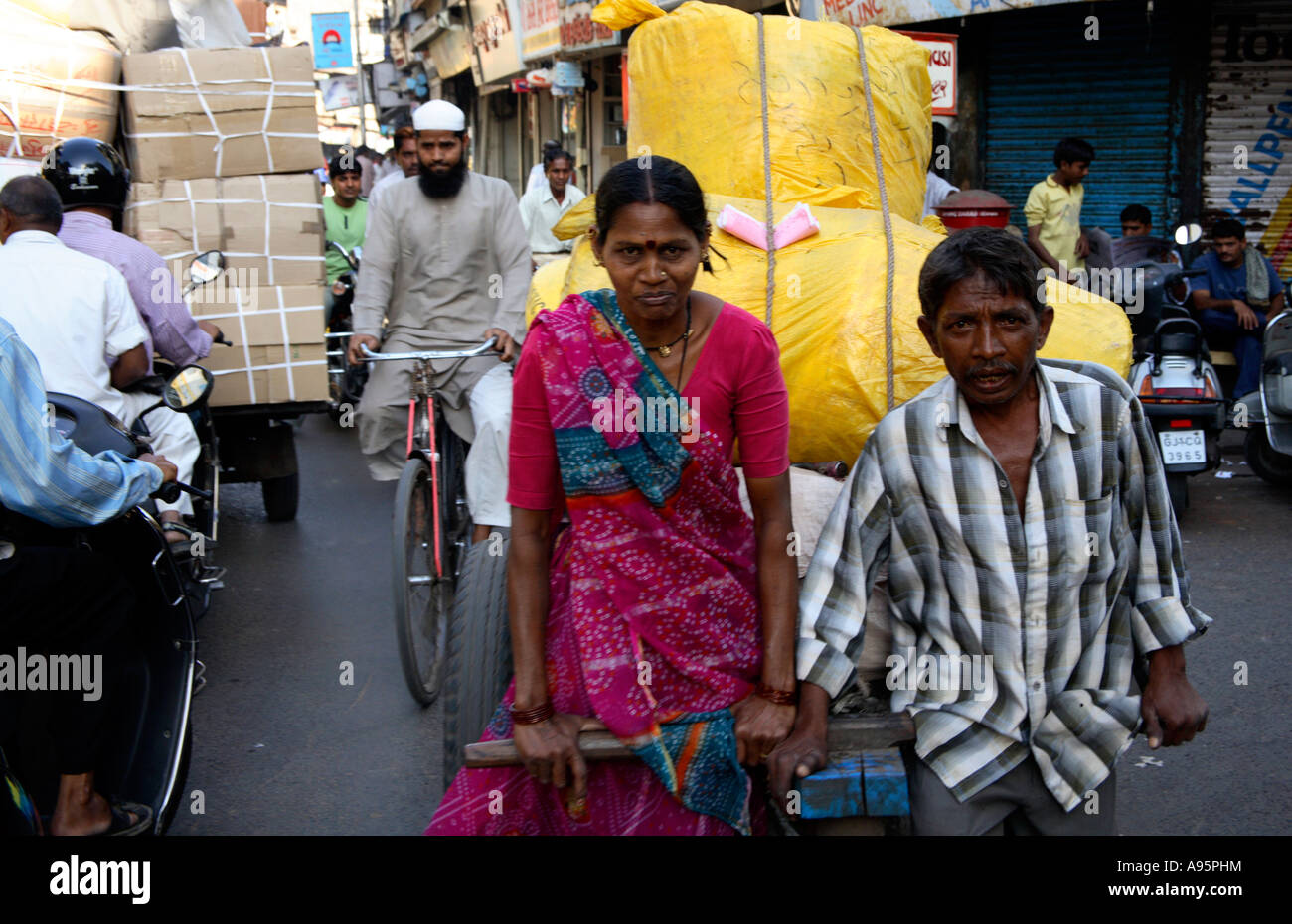 Indian female pulling loaded wagon through streets of Ahmedabad ...
