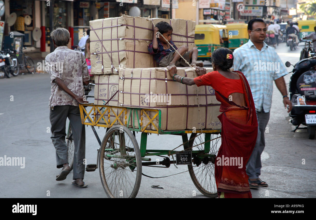 Indian female porter navigating wagon load through street, Ahmedabad ...