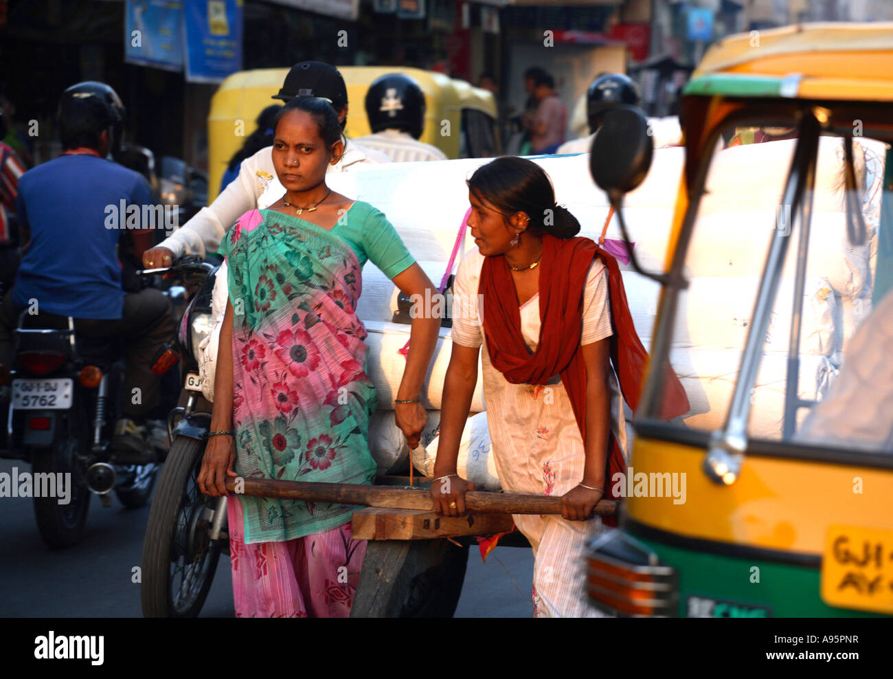 Two young female Indian porters dragging heavy wagon load through ...
