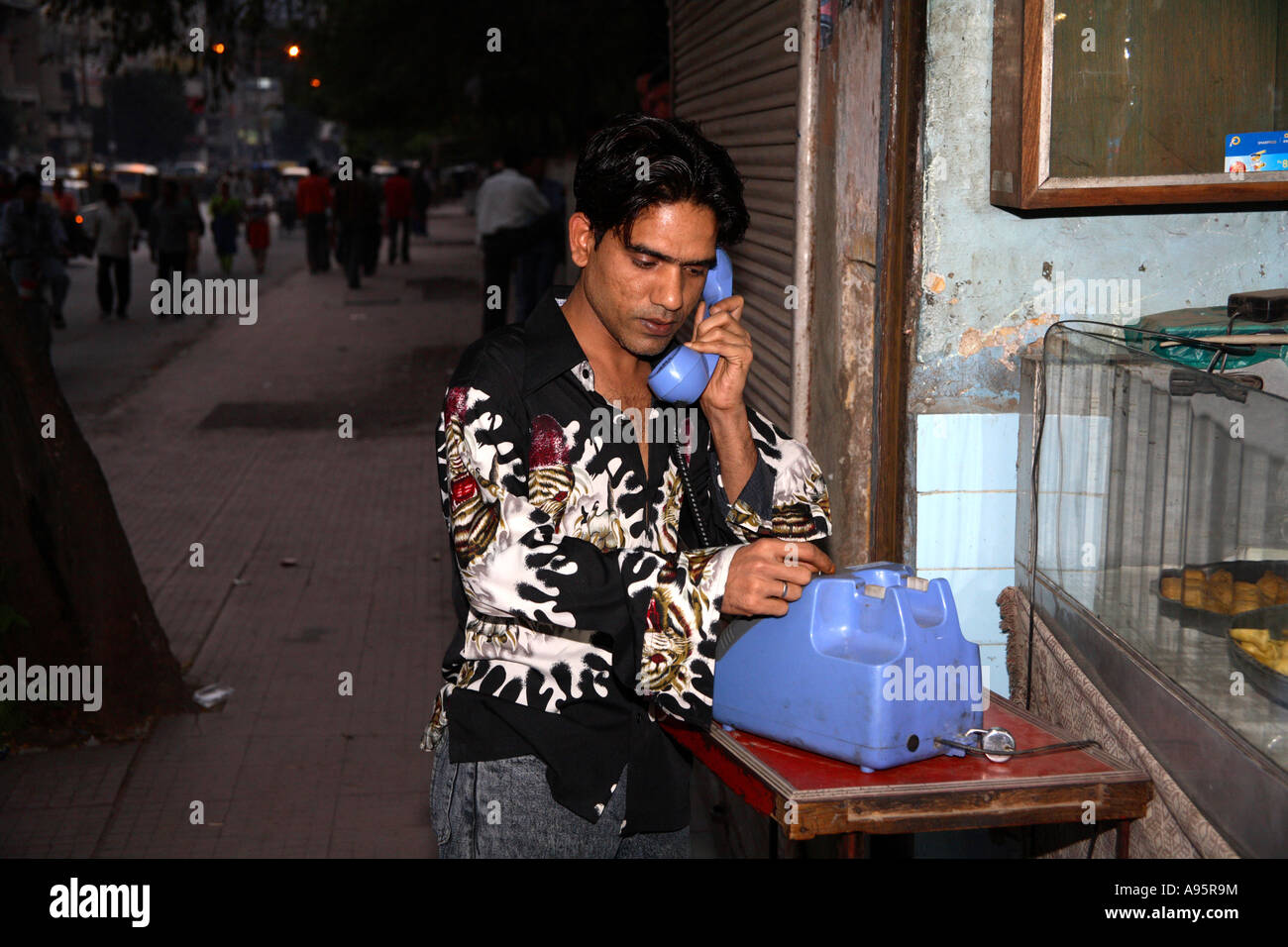 Young man making phone call on payphone at the side of the road ...