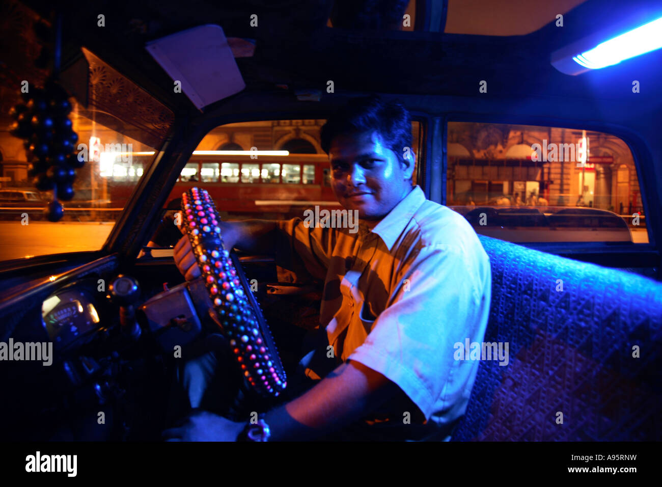 Indian Taxi Driver with neon light glowing inside his Padmini cab waits ...
