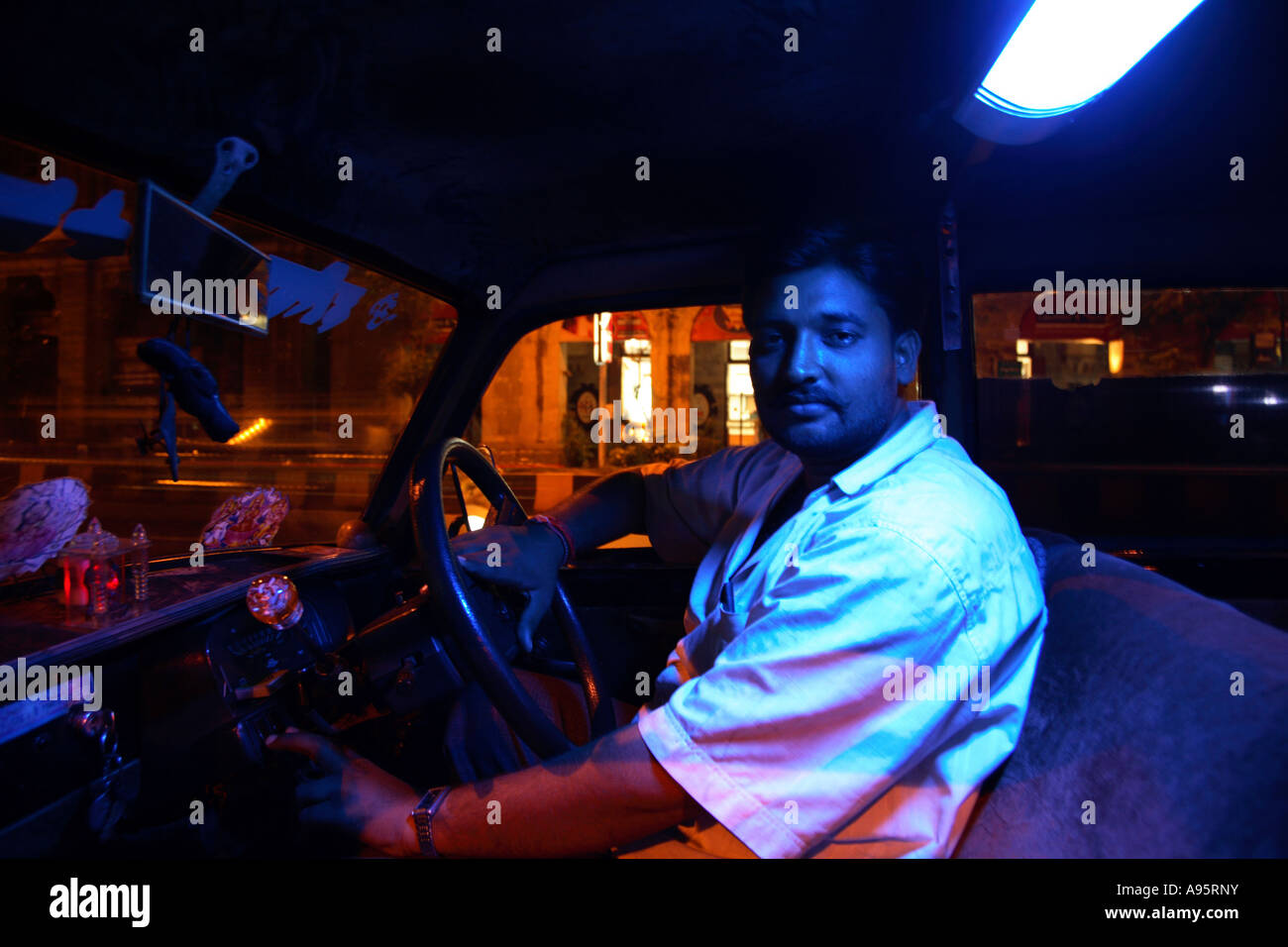 Indian Taxi Driver waiting for fare beneath neon light, Mumbai, India ...