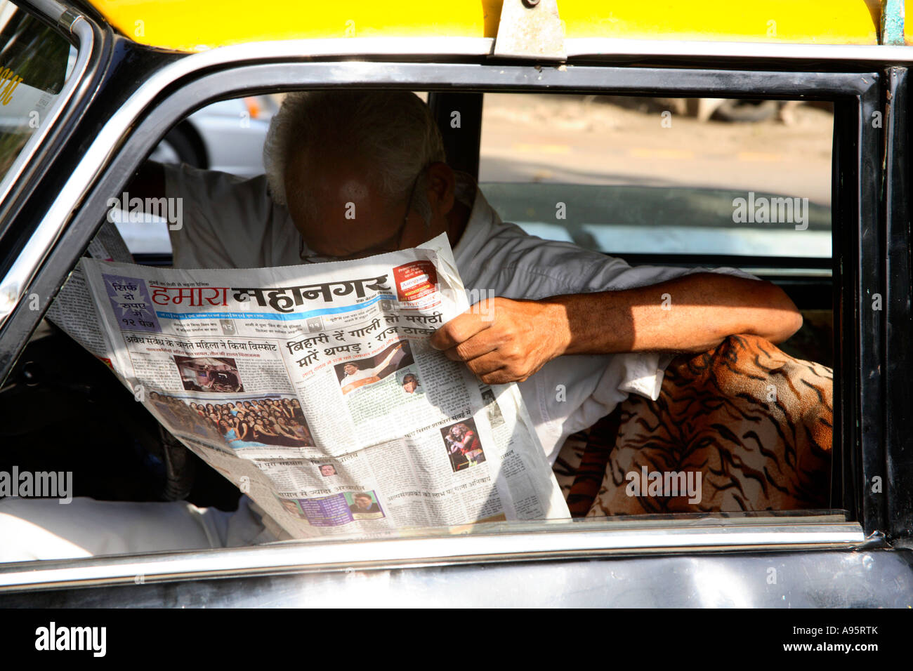 Indian Taxi driver reading Indian newspaper inside cab, Mumbai, India ...