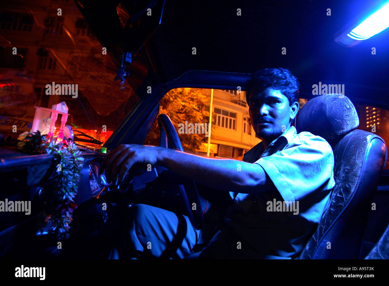 Indian Taxi Driver waiting for fare beneath neon lights, Mumbai, India ...