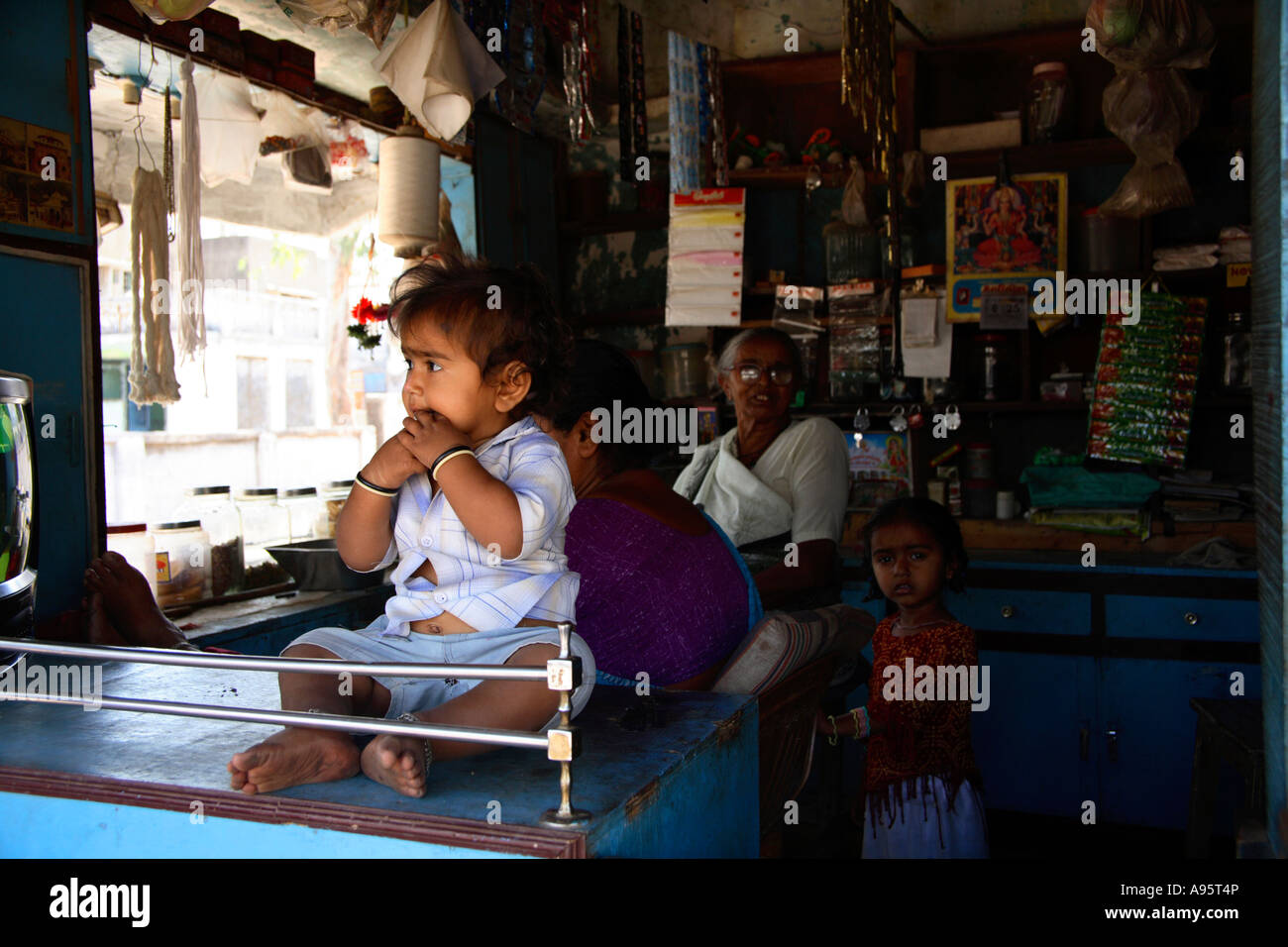 Young Indian child sat on counter at convenience store in Champaner ...