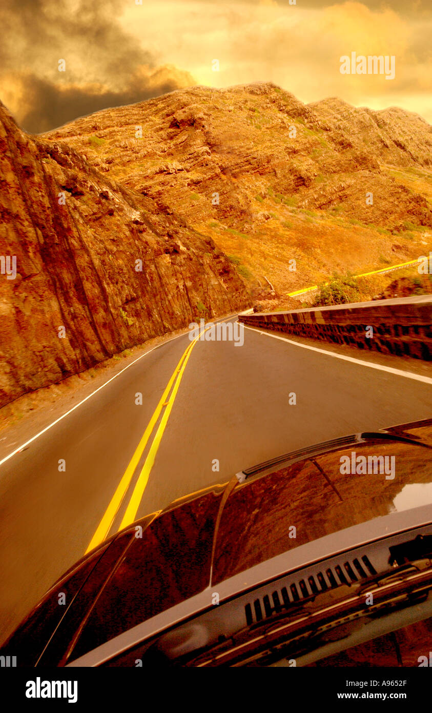 Vertical color image of a car driving on a winding road along the ocean ...