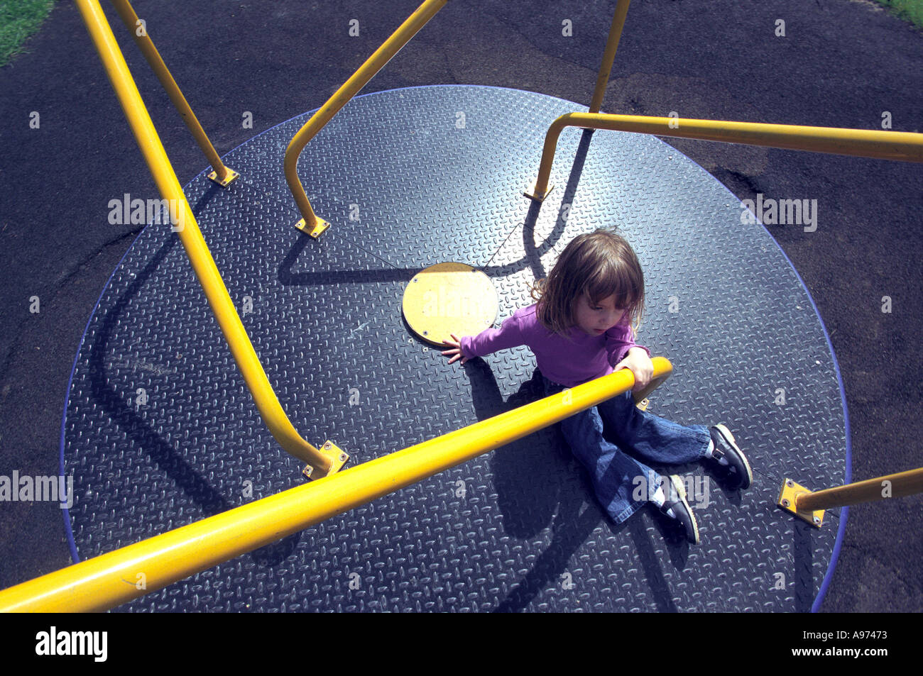 A small girl sits alone on a roundabout Stock Photo - Alamy