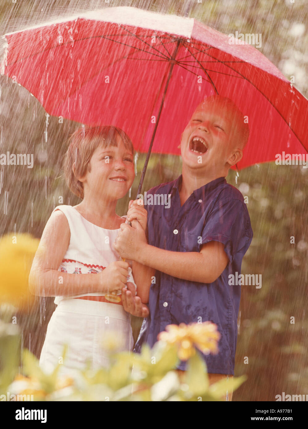 boy and girl playing in rain with umbrella Stock Photo - Alamy
