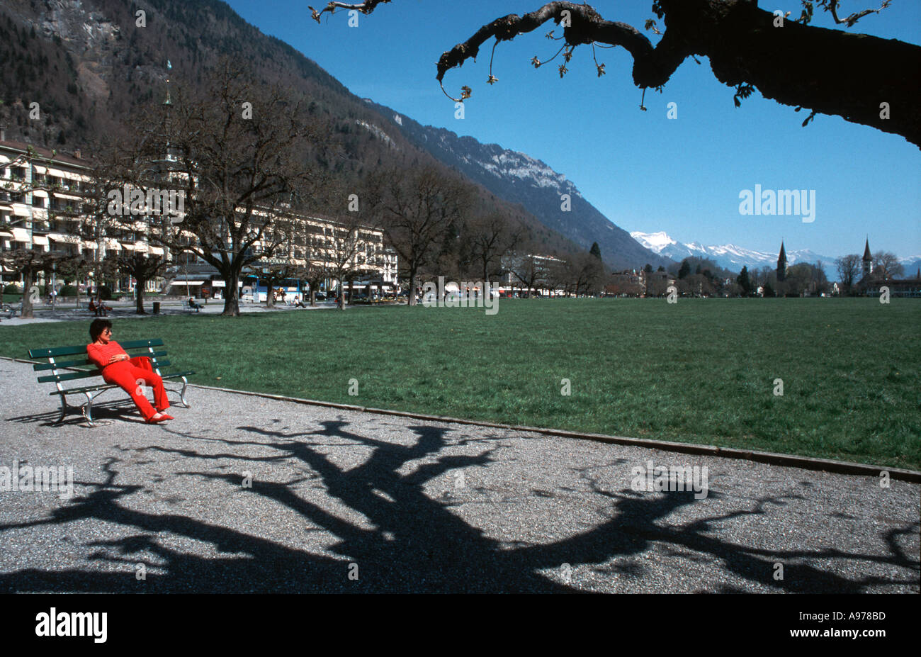 Figure dressed in red relaxing beside an expanse of deep green grass in ...
