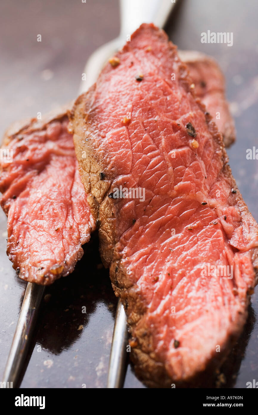 Two slices of beef steak on meat fork FoodCollection Stock Photo - Alamy