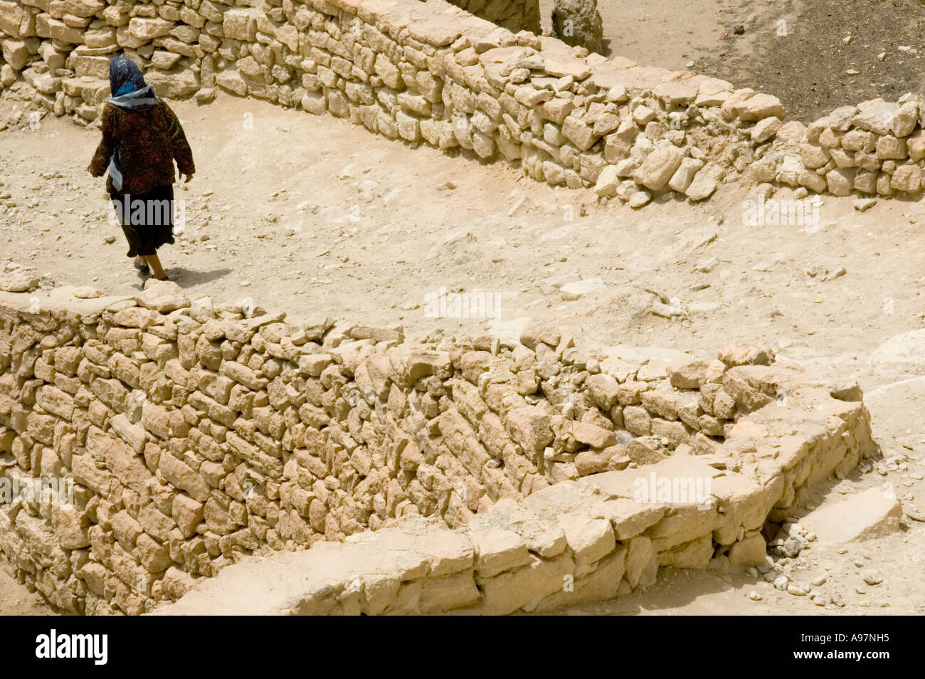 Traditionally dressed woman walking to market in the town of Chenini ...