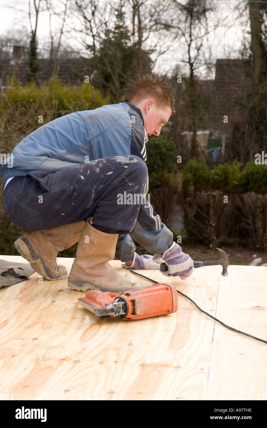 a carpenter nailing down wooden sheets to form a flat roof Stock Photo ...