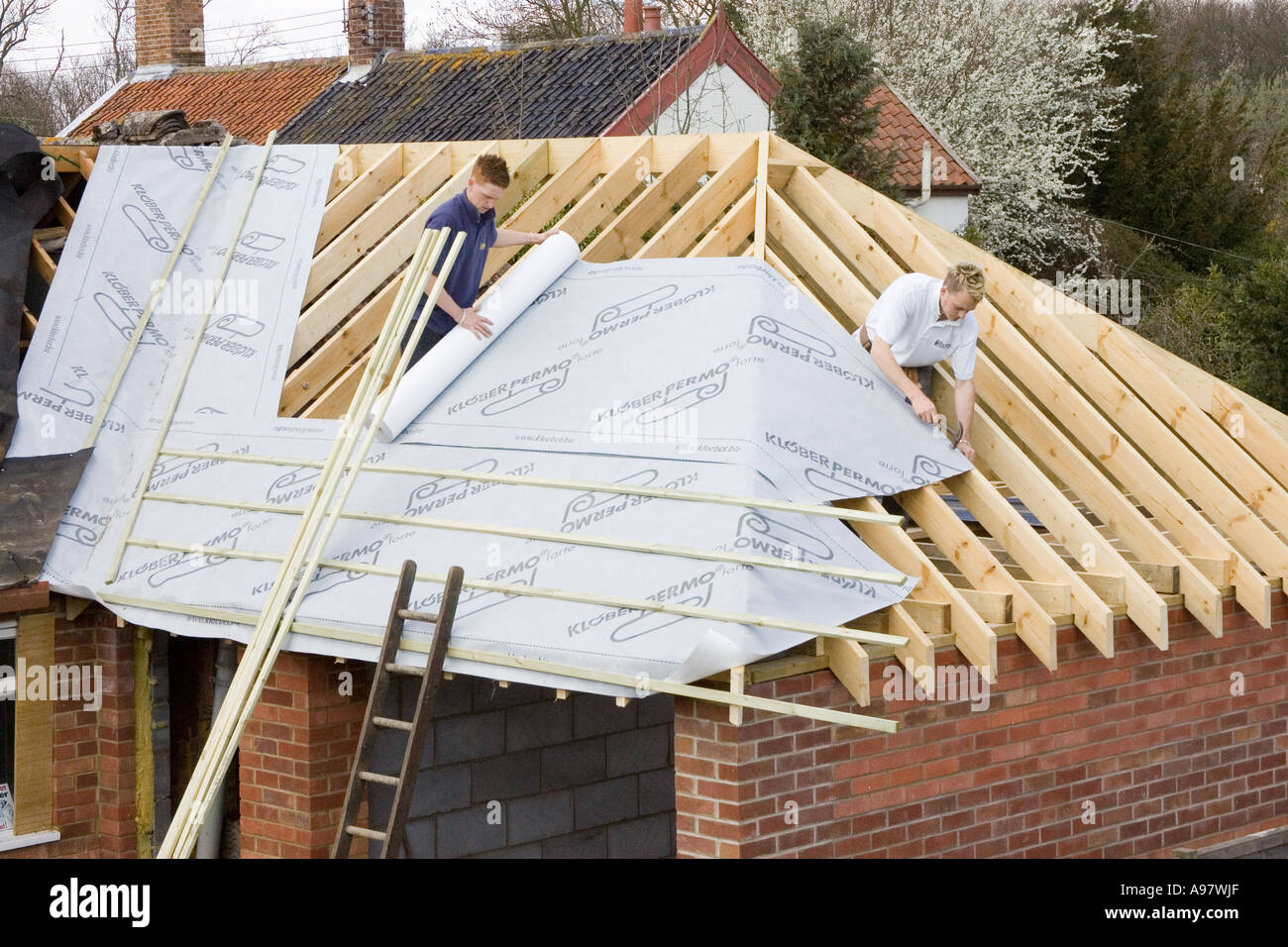 builders fitting roofing felt membrane to a new roof Stock Photo - Alamy