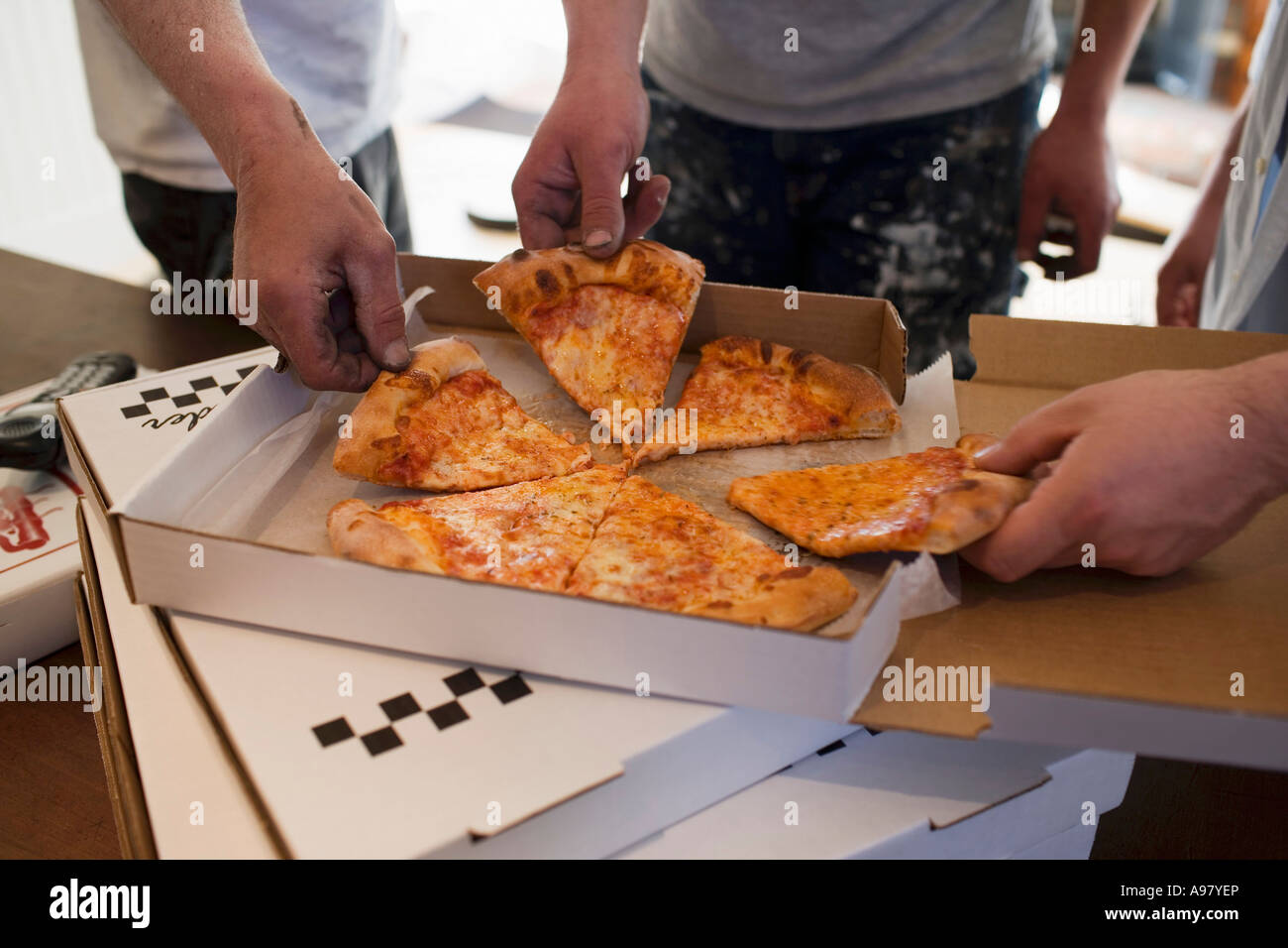 Workers taking pieces of pizza out of pizza box FoodCollection Stock ...