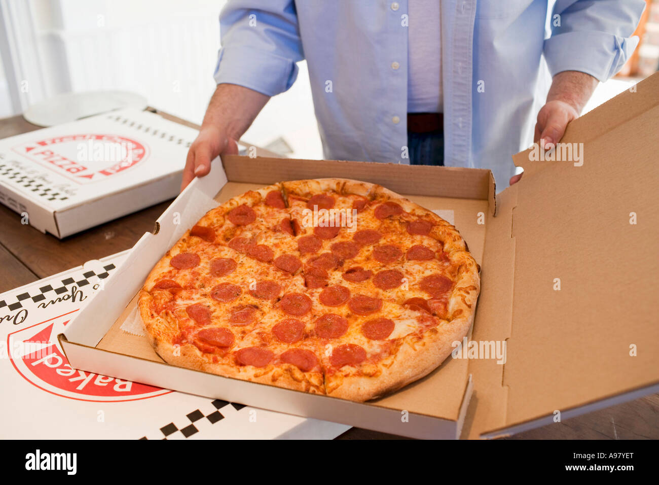 Man holding pizza box containing pepperoni pizza FoodCollection Stock ...