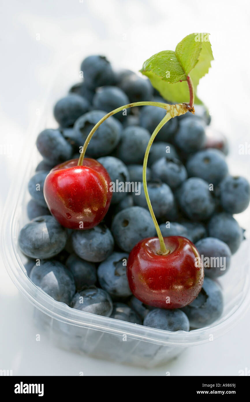 Blueberries and two cherries in plastic punnet FoodCollection Stock ...