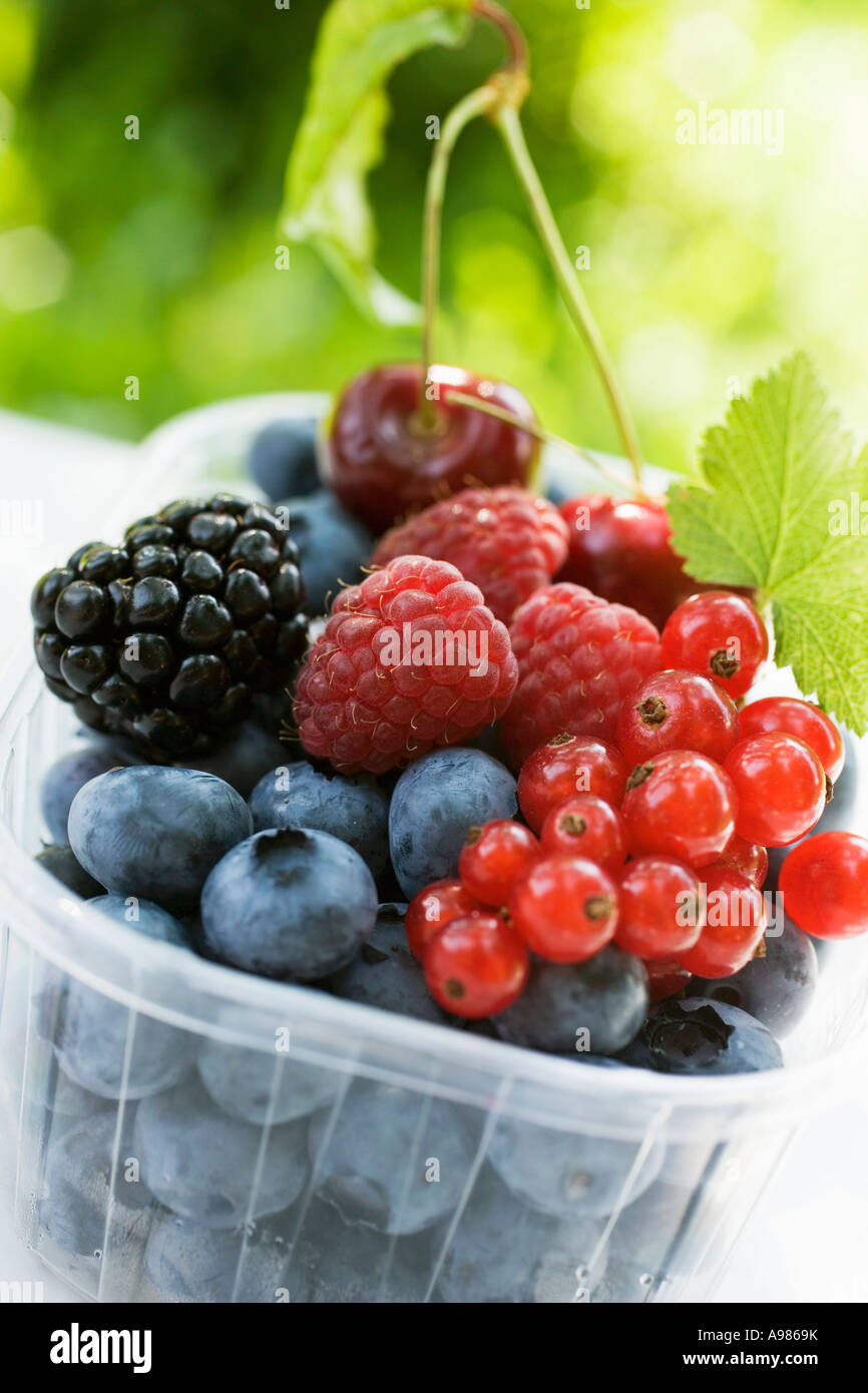 Assorted berries and two cherries in plastic punnet FoodCollection ...