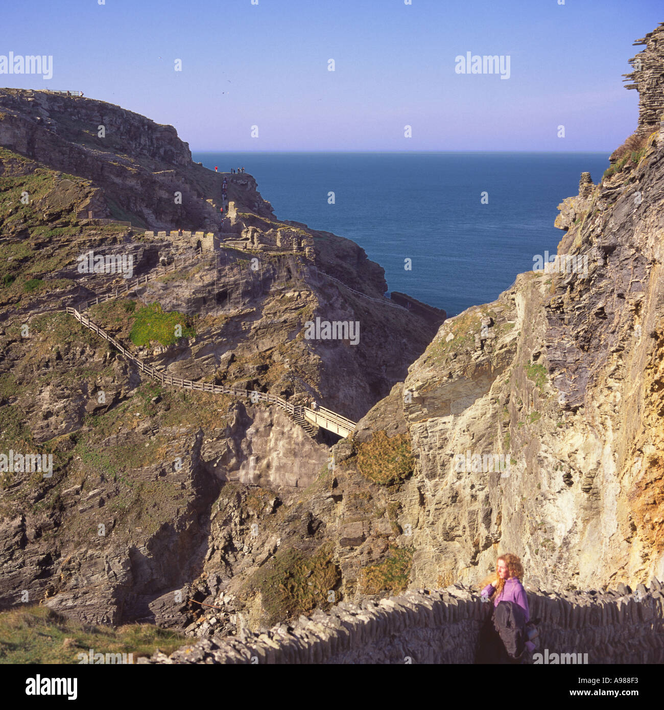 Young woman admiring sunlit cliffs evening view with footbridge and ...